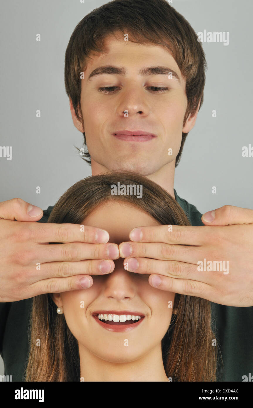 Young adult male holding hands over woman's eyes Stock Photo - Alamy