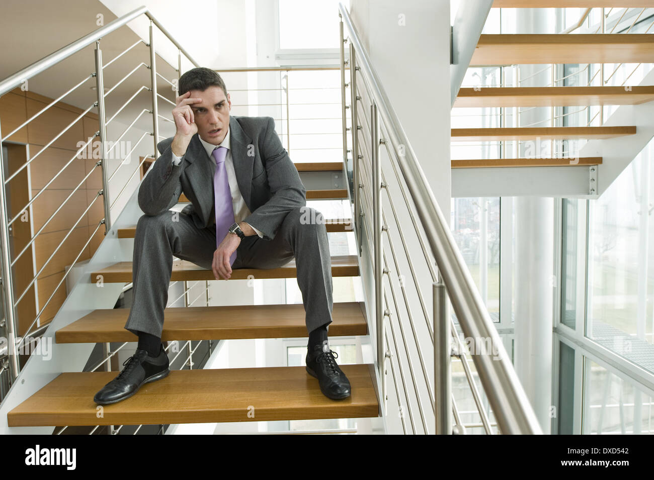 Businessman on office staircase holding his head Stock Photo - Alamy