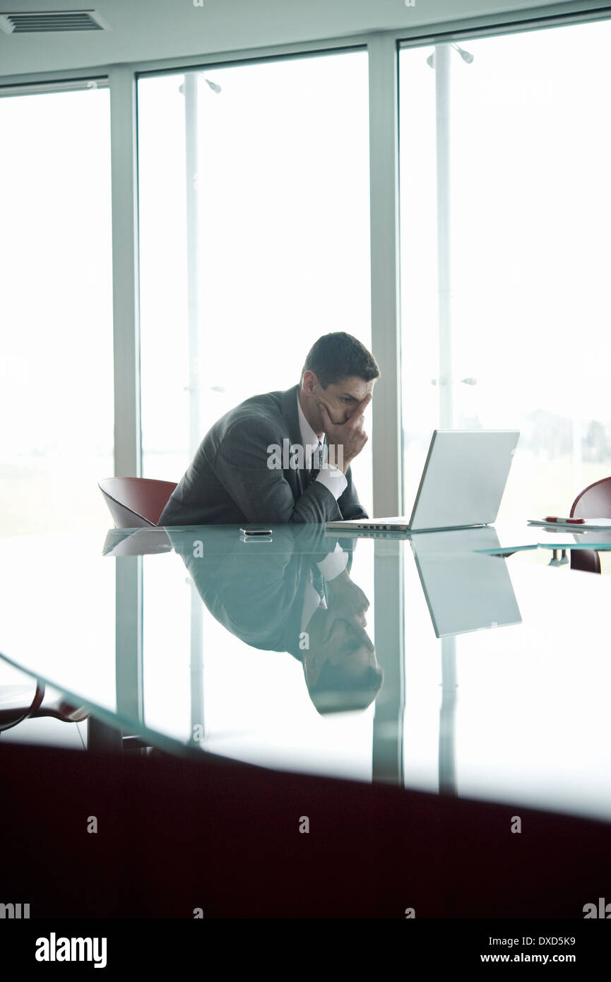 Businessman at laptop computer with his face in his hand Stock Photo ...