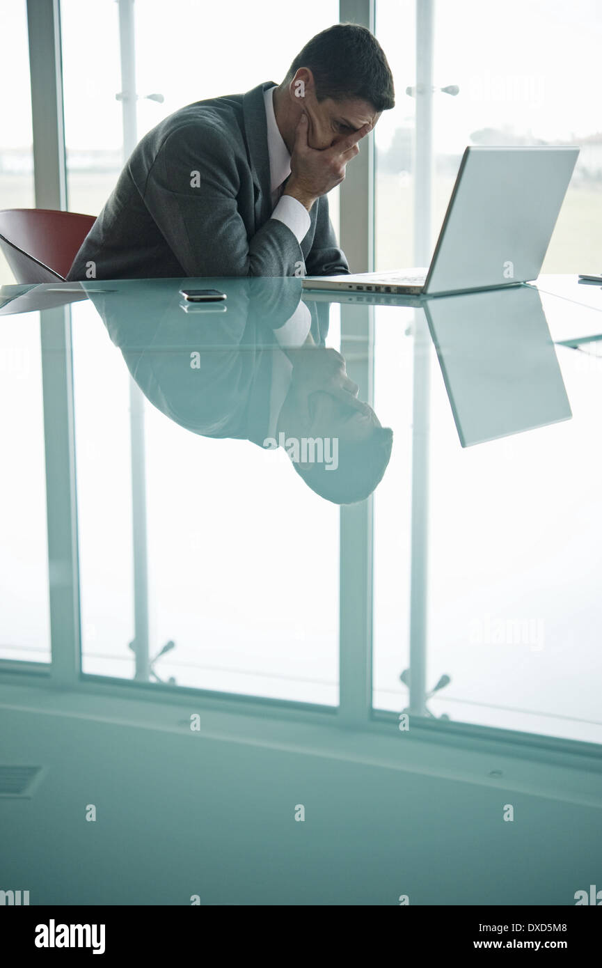 Businessman at laptop computer with his face in his hand Stock Photo ...