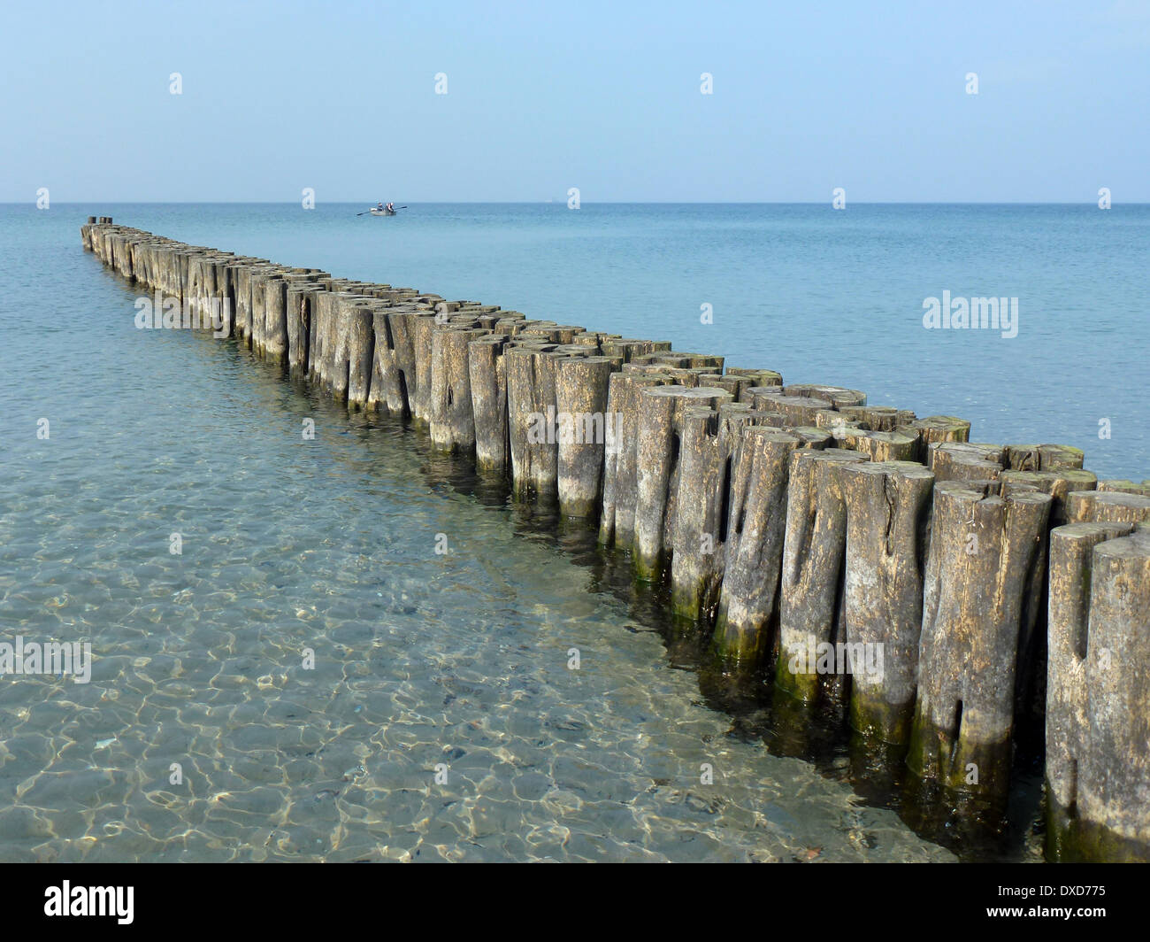 A column of wooden groynes stretch from the beach into the water of the ...