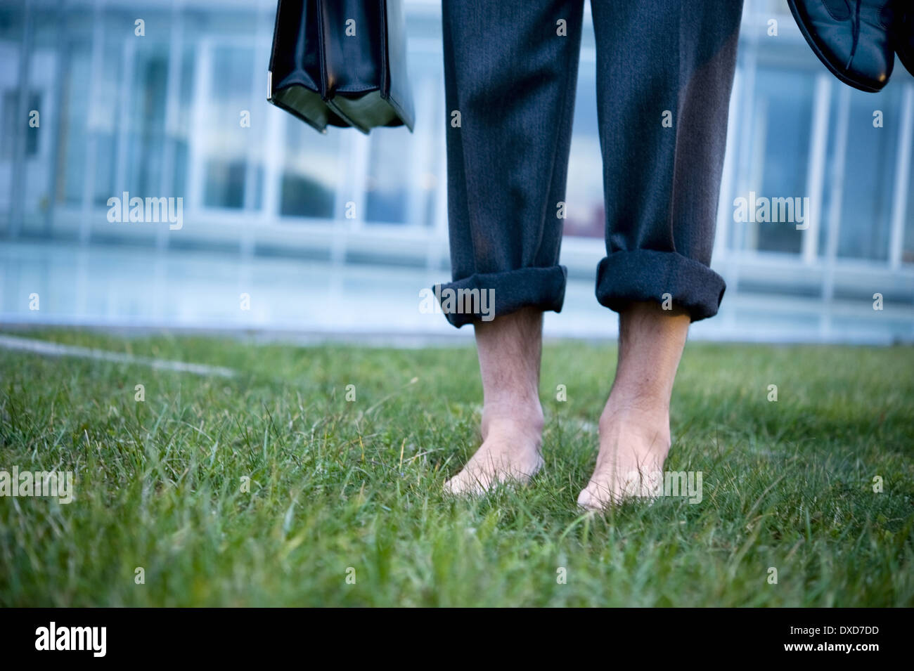 Businessman's bare feet on grass outside of office building Stock Photo ...