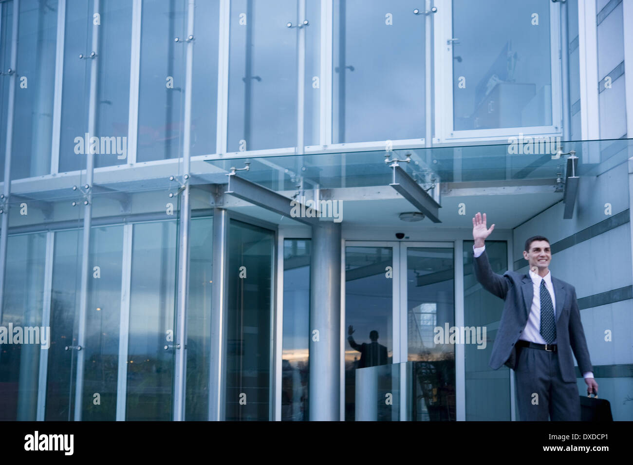 Businessman waving while exiting from office building Stock Photo - Alamy
