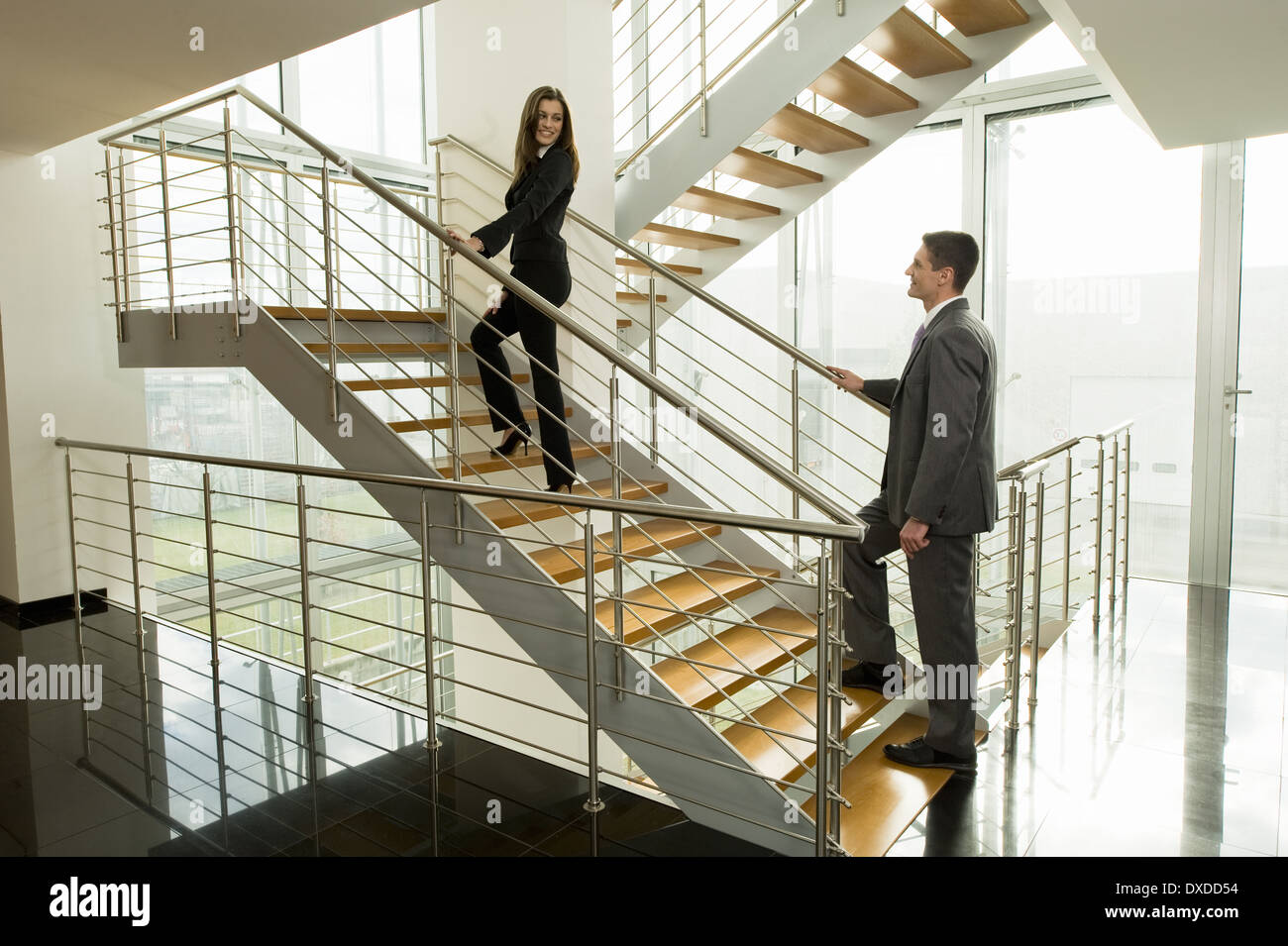Businesswoman and businessman walking up office staircase Stock Photo ...