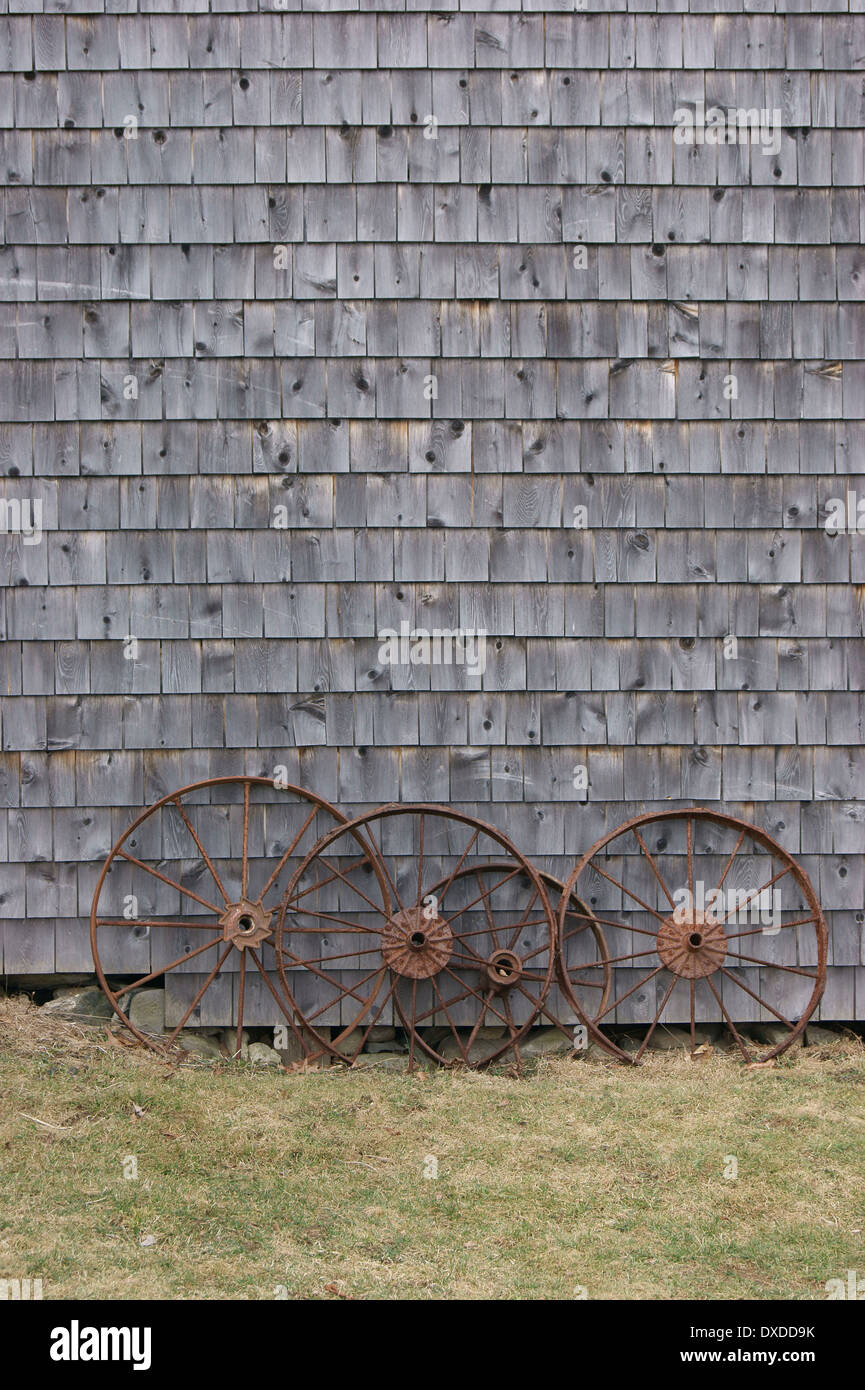 Rusty iron wheel rims leaning against a barn, Maine Stock Photo - Alamy