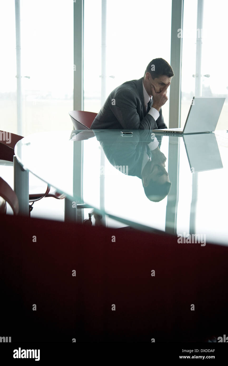 Businessman at laptop computer with his face in his hand Stock Photo ...