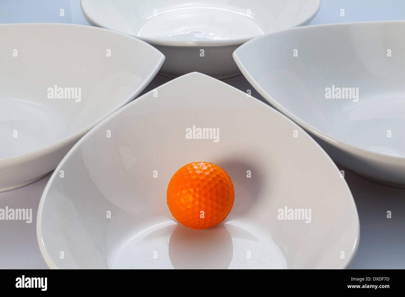 Four white ceramics bowls and golf ball Stock Photo - Alamy