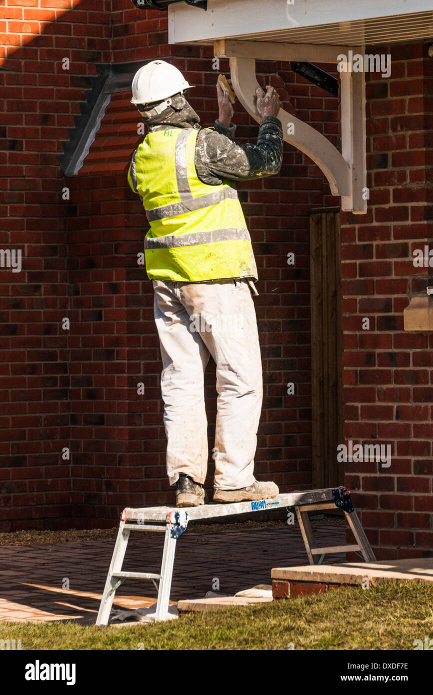 Worker putting finishing touches to the exterior of a newly built house ...