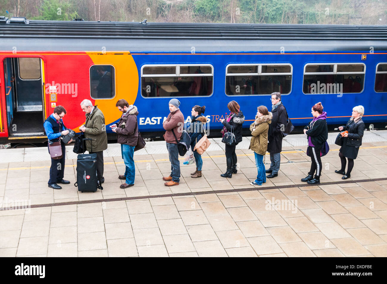 A queue of train passengers getting tickets from a train guard on the ...