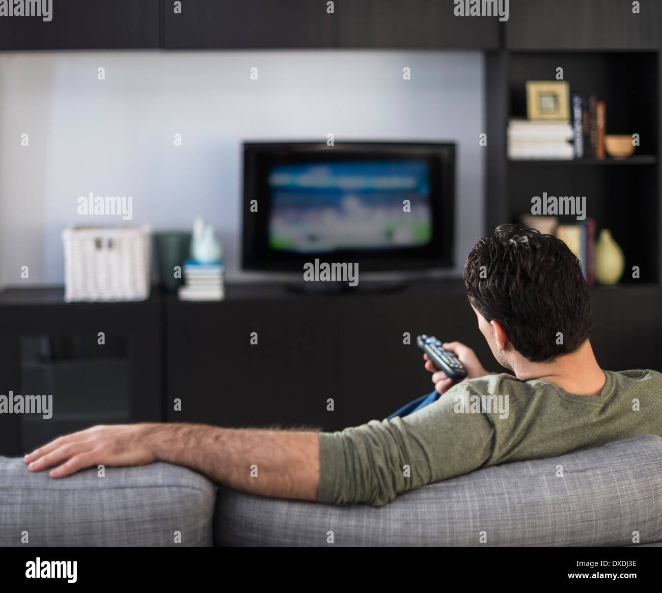 Rear view of man watching tv Stock Photo - Alamy