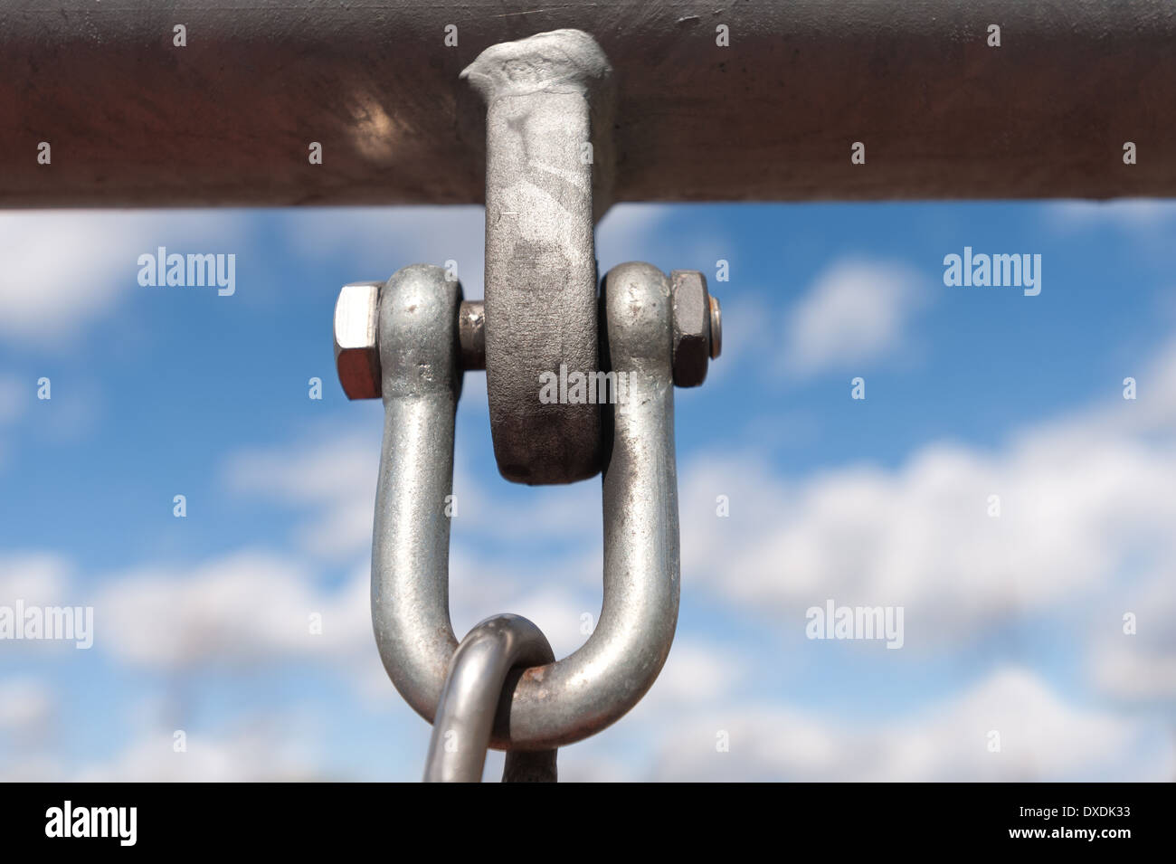 Strong galvanized steel shackle hanging against blue sky and clouds ...