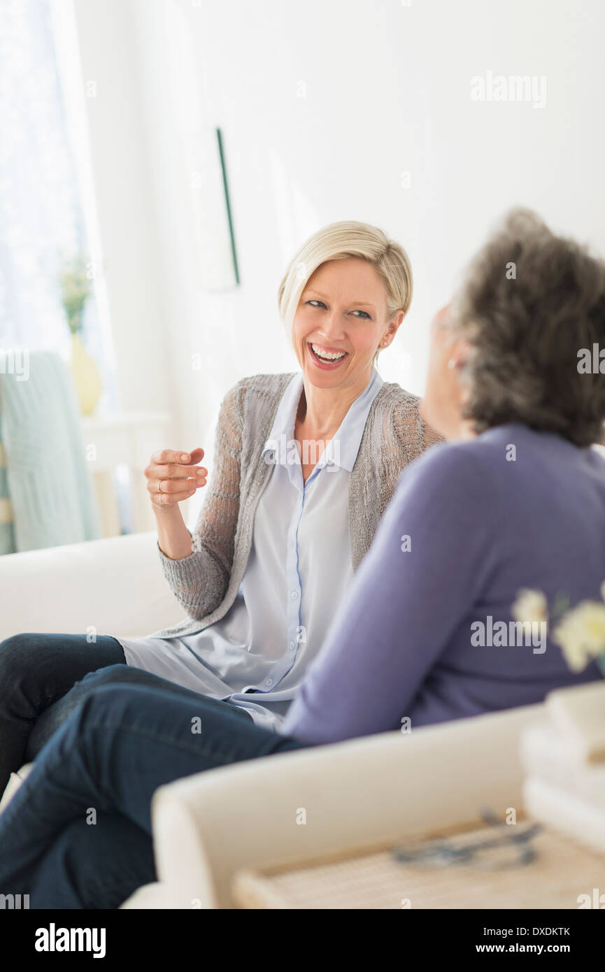 Two women sitting on coach talking Stock Photo - Alamy