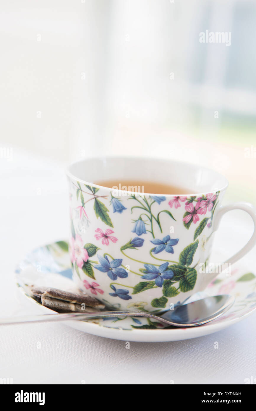 Cup of tea in pretty floral cup with saucer and used tea bag, studio ...