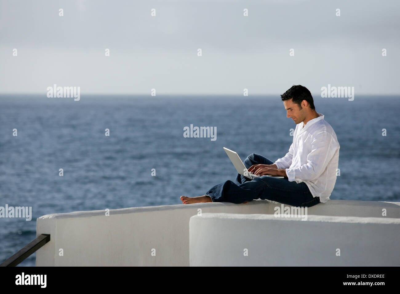 Man with computer in front of the sea Stock Photo - Alamy