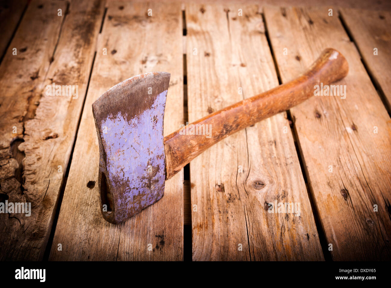 An old hatchet axe with a wooden handle and wear marks sits on a rough ...