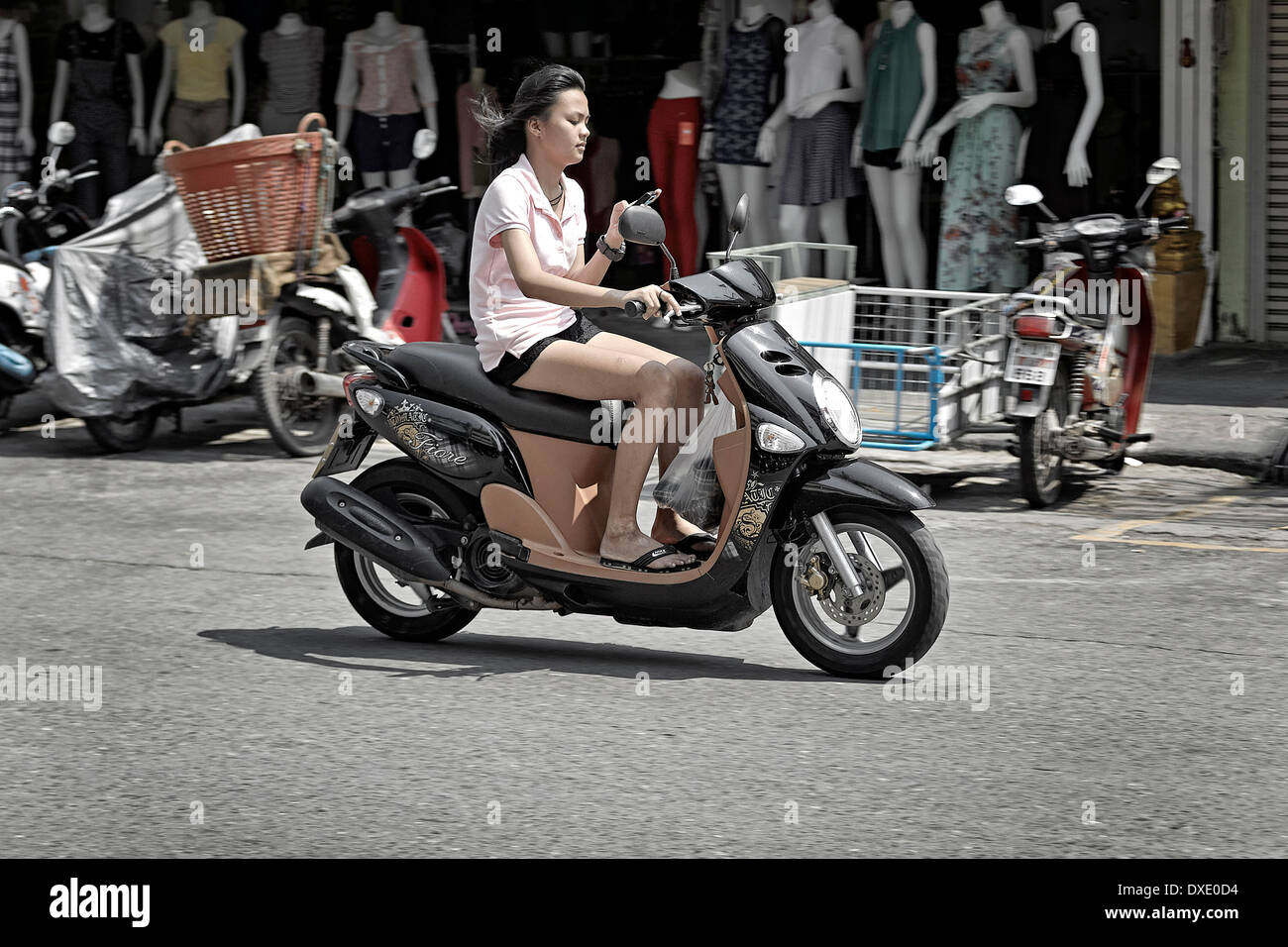 Girl riding motorbike and using a mobile phone. Her legs show scars and ...