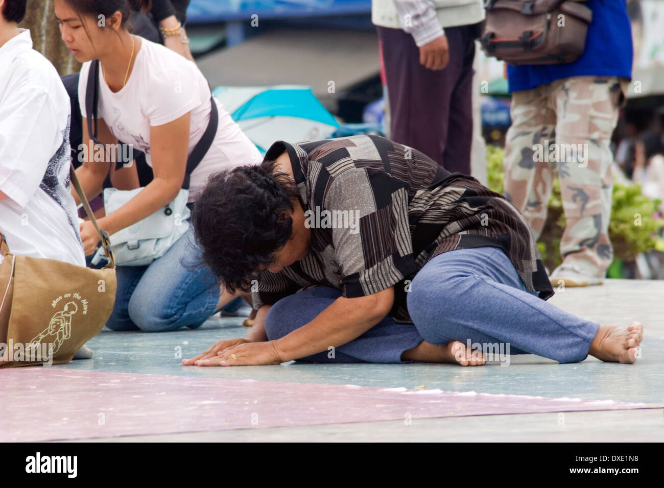 A women is bowing in worship while holding lotus flowers in Khorat ...