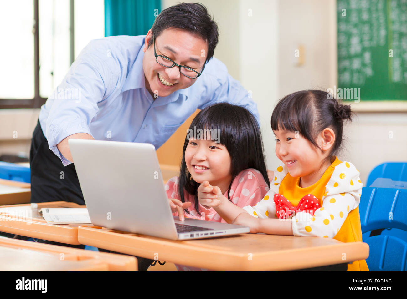 Teacher teaching children with a laptop in classroom Stock Photo - Alamy
