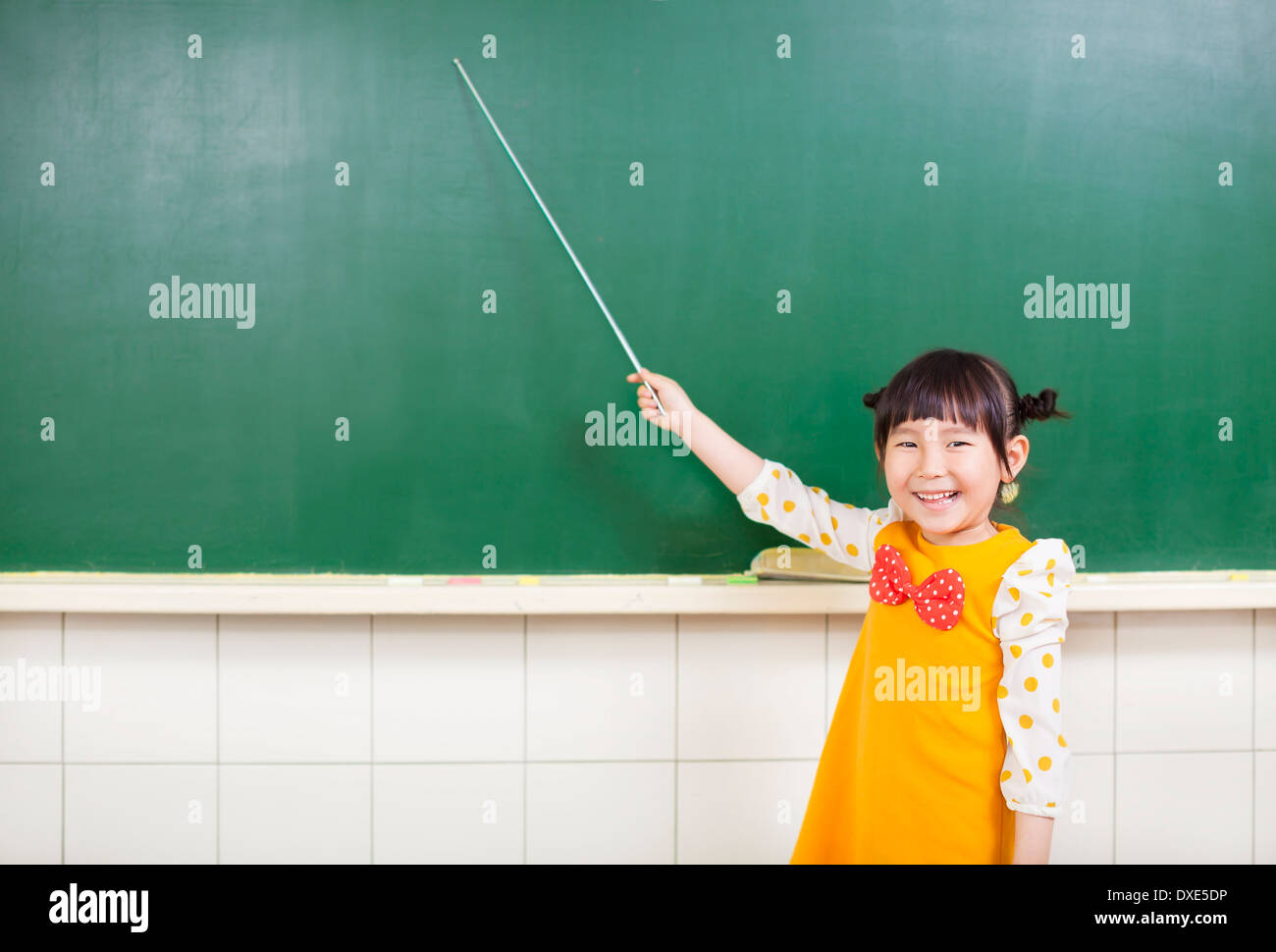 smiling girl using a baton to point on a blackboard Stock Photo - Alamy