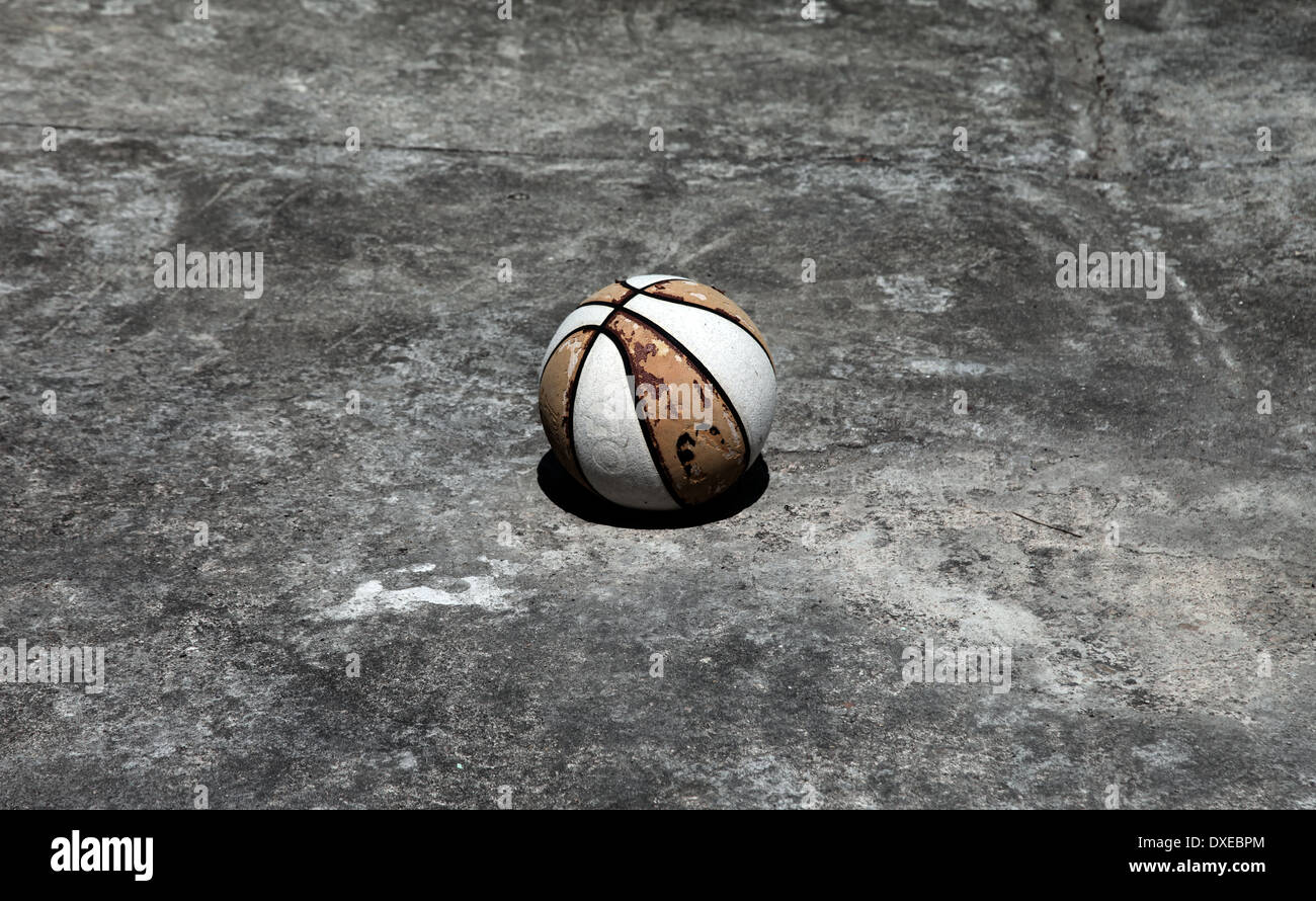 It's a photo of a basketball ball on a concrete rough floor. It's a kid ...