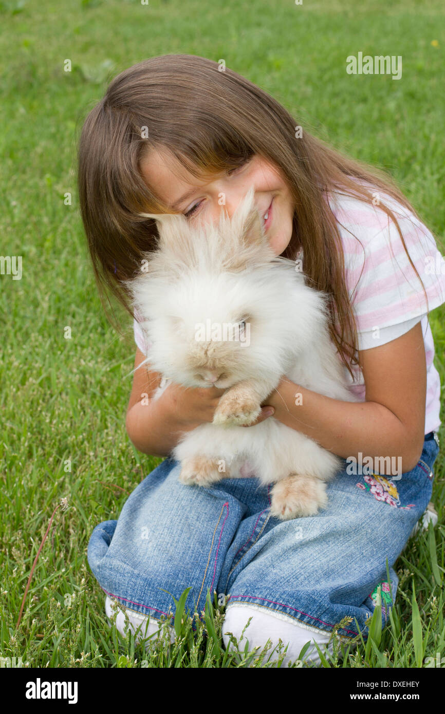 Girl (7 years old) with a dwarf teddy rabbit in her arms. Germany Stock ...