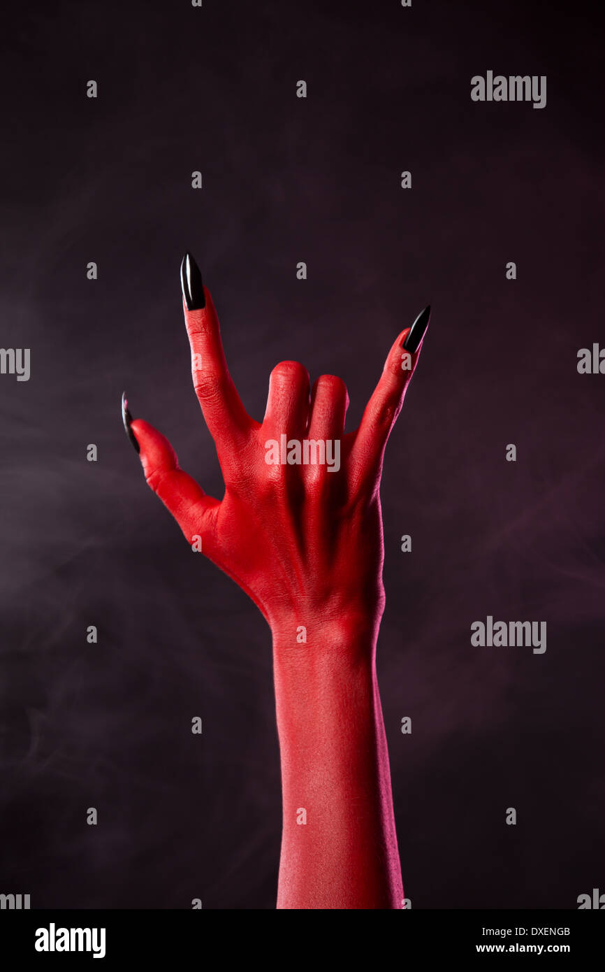 Red devil hand showing heavy metal gesture, studio shot on smoky ...