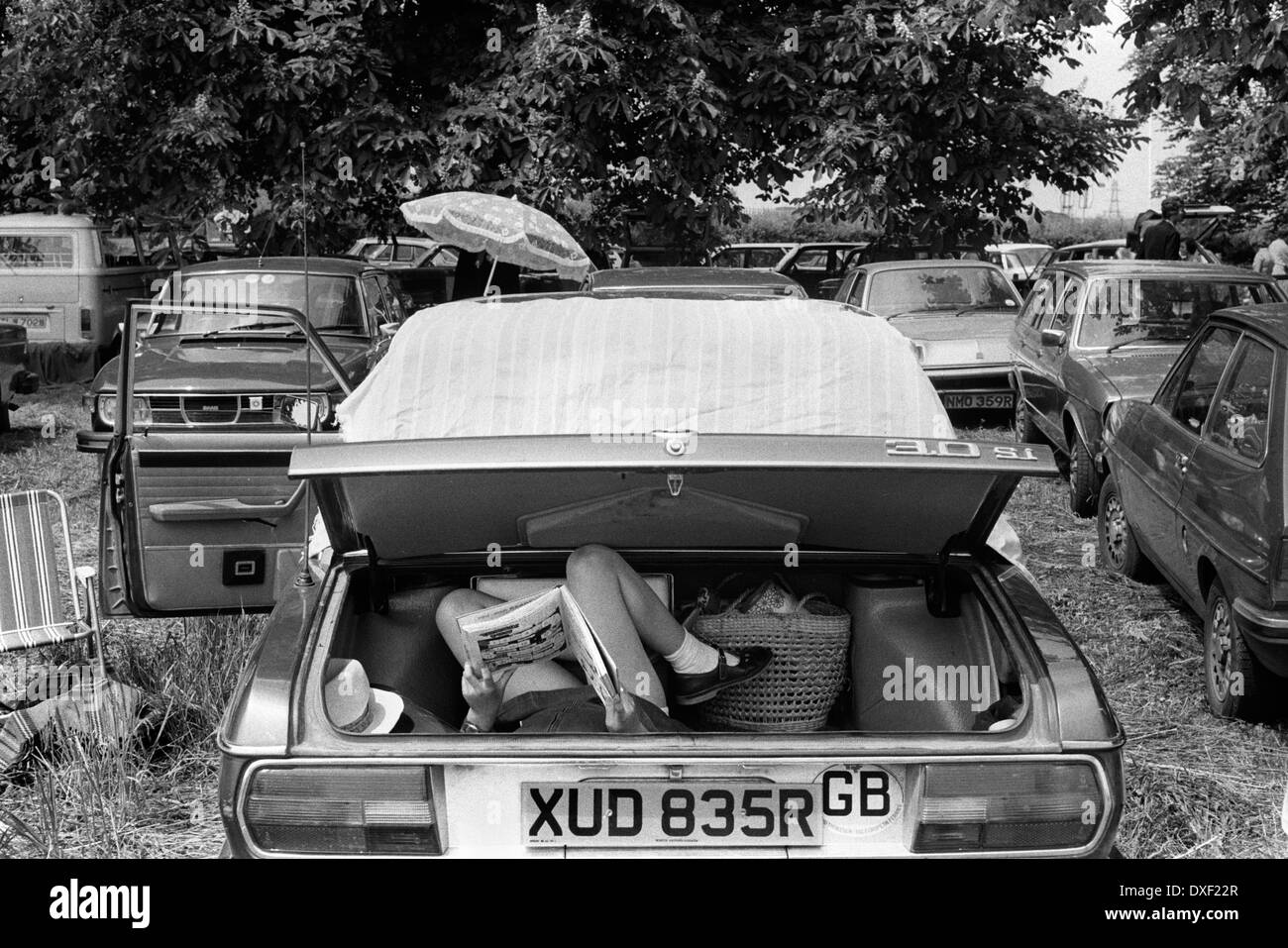 Child reading a comic in the boot, the back of her parents car. Windsor ...
