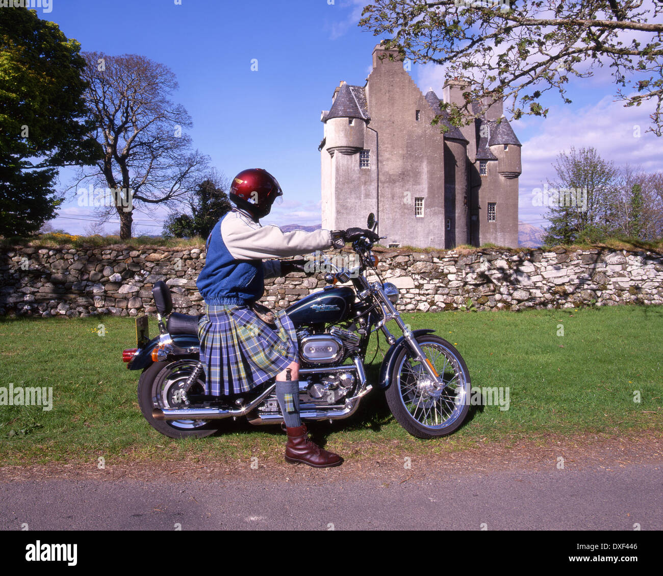 Scots motorcycle rider on a harley Davidson pauses at Barcaldine castle ...