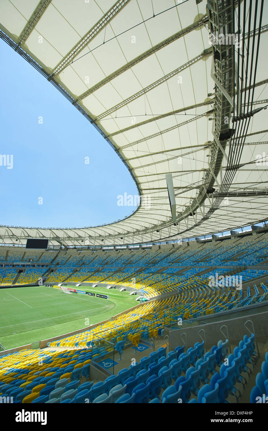 Empty blue and yellow stadium seating surrounding green pitch at ...