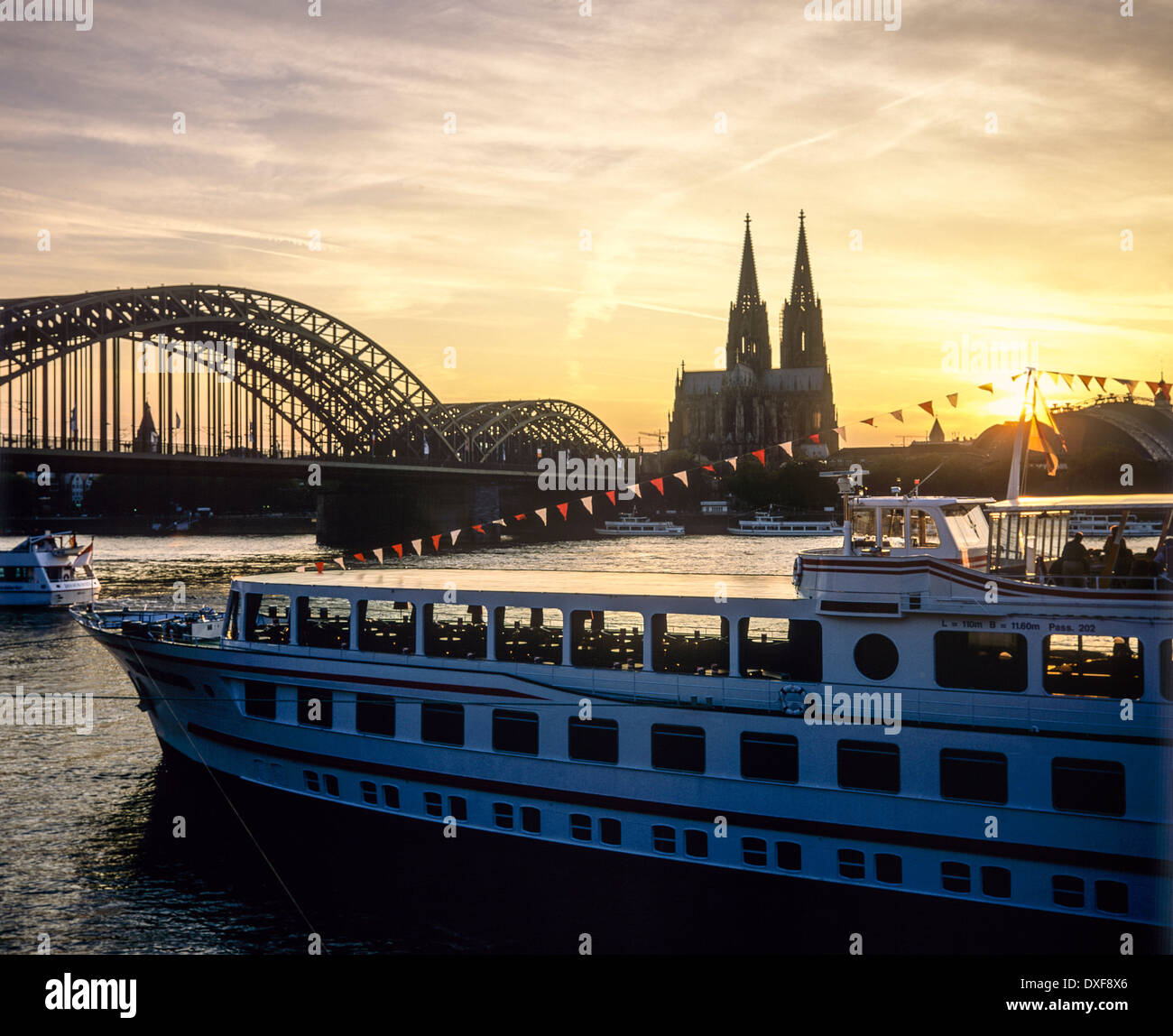 Cruise boat and Hohenzollern bridge and cathedral at sunset Cologne ...