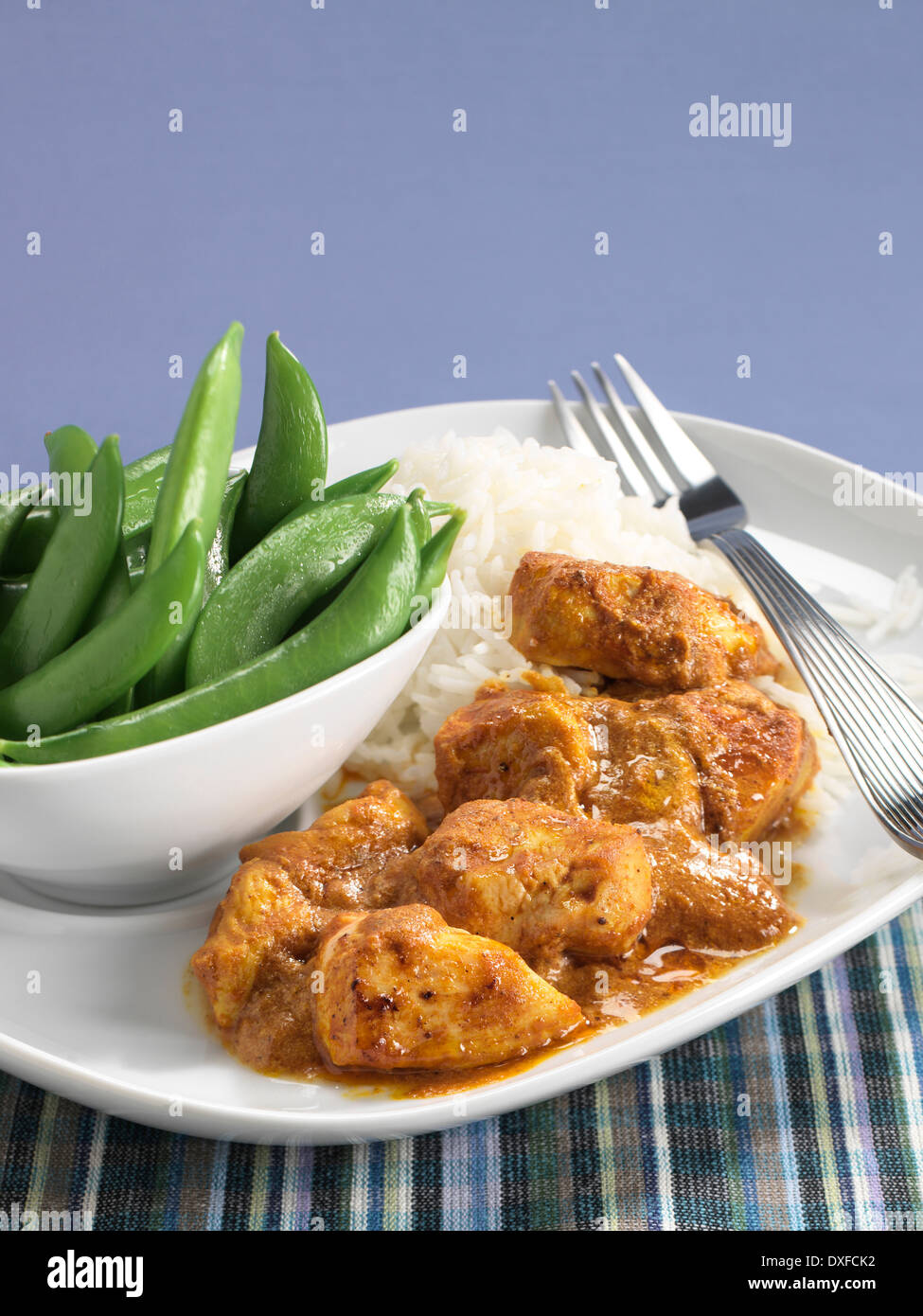 Butter Chicken and rice on plate with bowl of snap peas, studio shot ...
