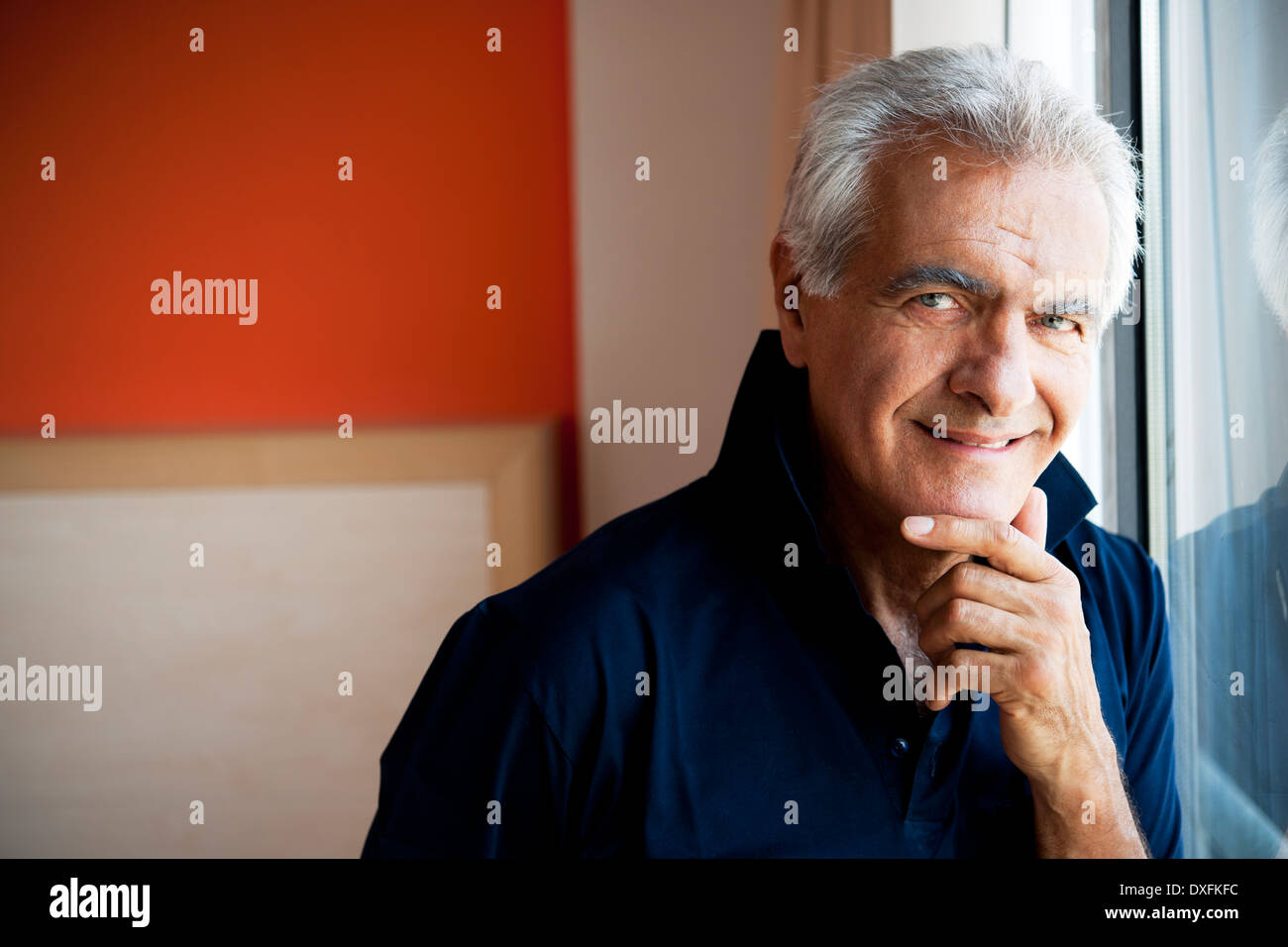 Mature man standing at window Stock Photo - Alamy