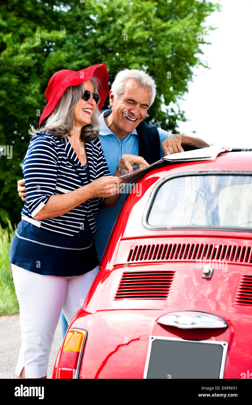 Mature couple enjoying a road trip in a small red car Stock Photo - Alamy