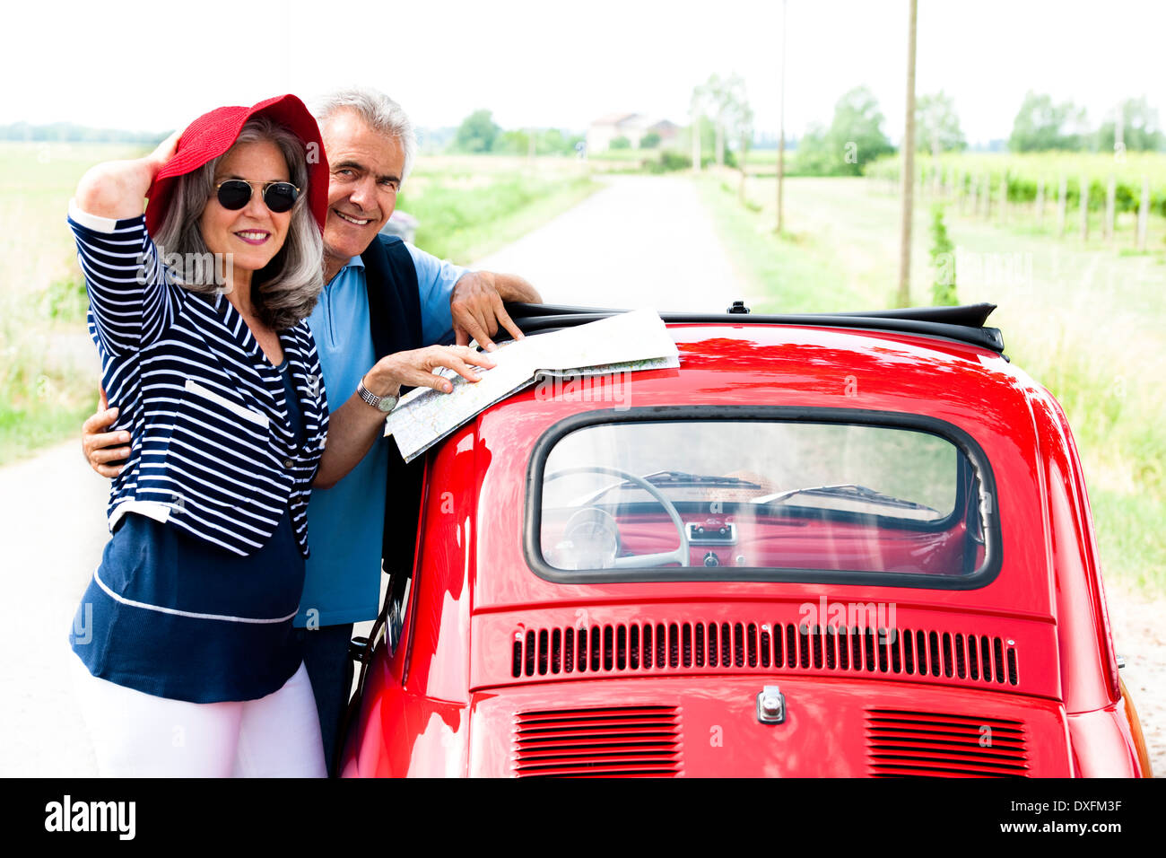Mature couple enjoying a road trip in a small red car Stock Photo - Alamy