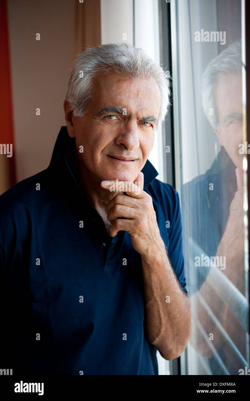 Mature man standing at window Stock Photo - Alamy