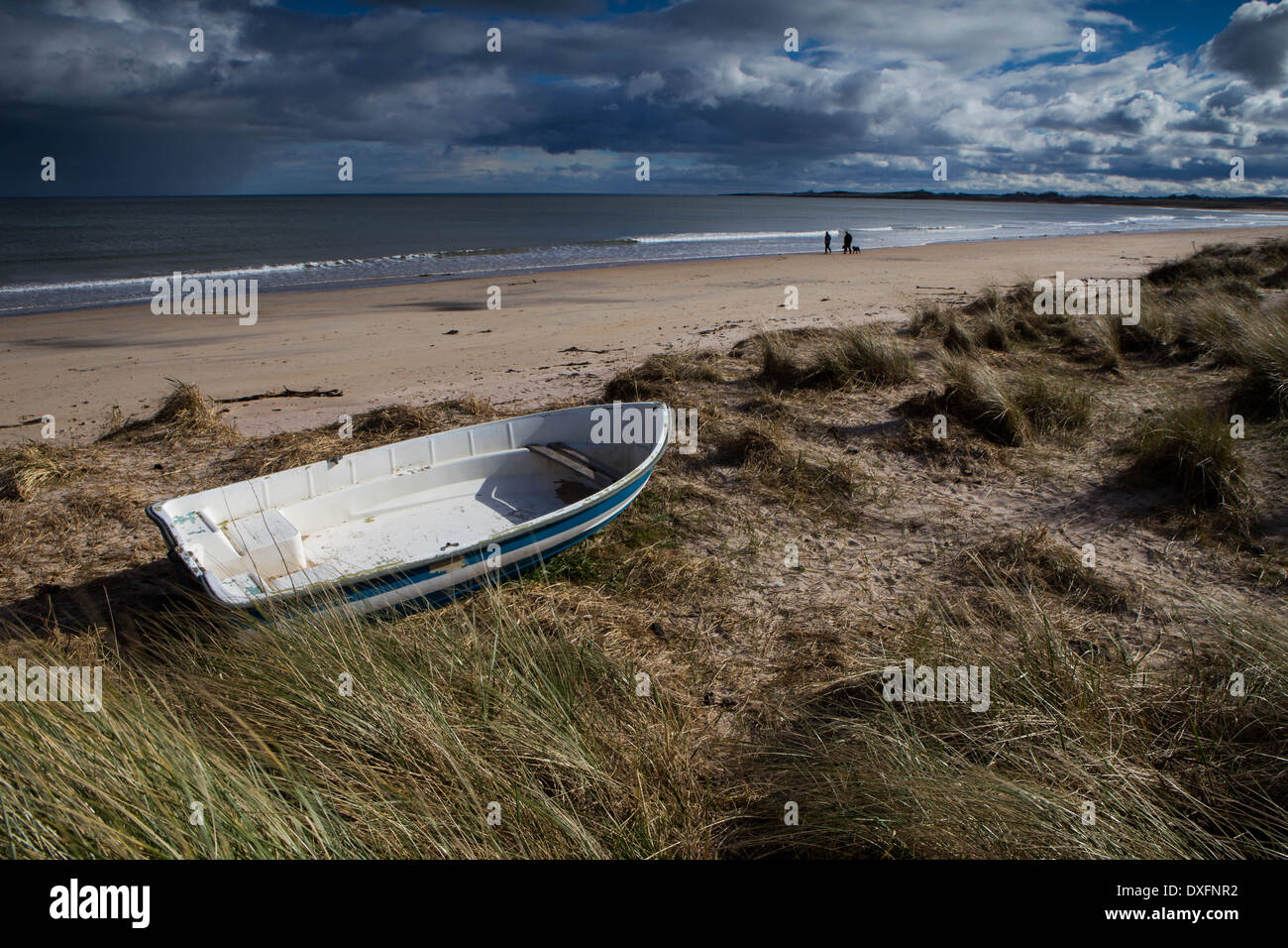 Small rowing boat on the beach with a couple in the distance Stock ...