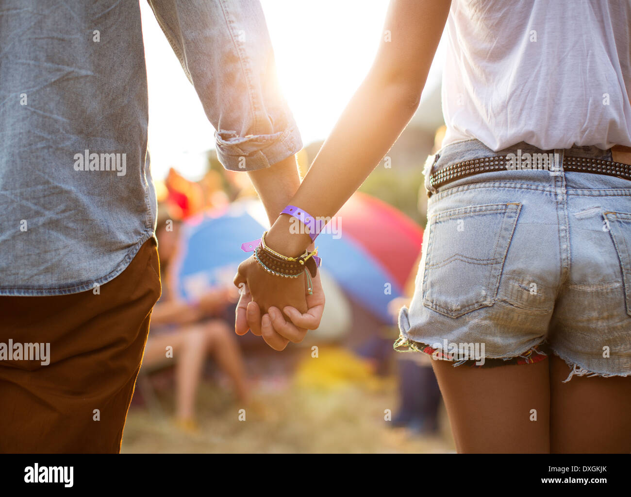 Couple holding hands near tents at music festival Stock Photo - Alamy