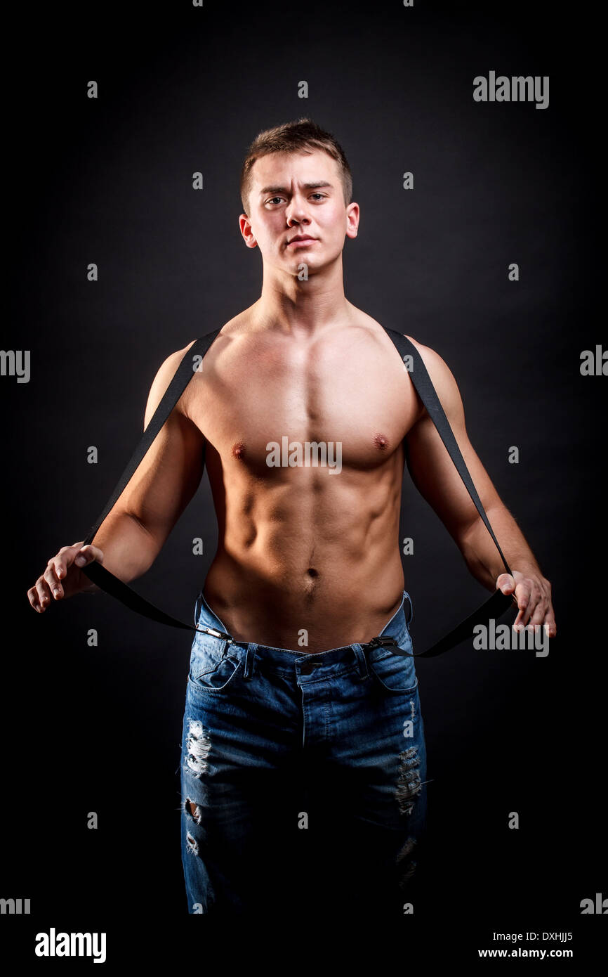 Portrait of a handsome well-built man posing in short jeans and ...