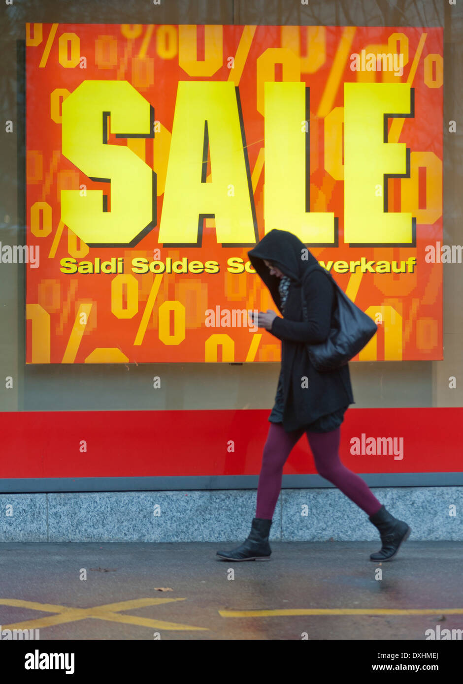 People passing by a "sales" advertisement sign in a shop window in ...