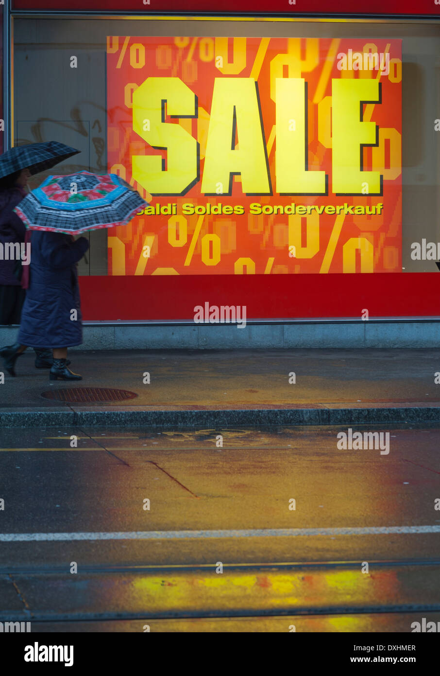 People passing by a "sales" advertisement sign in a shop window in ...
