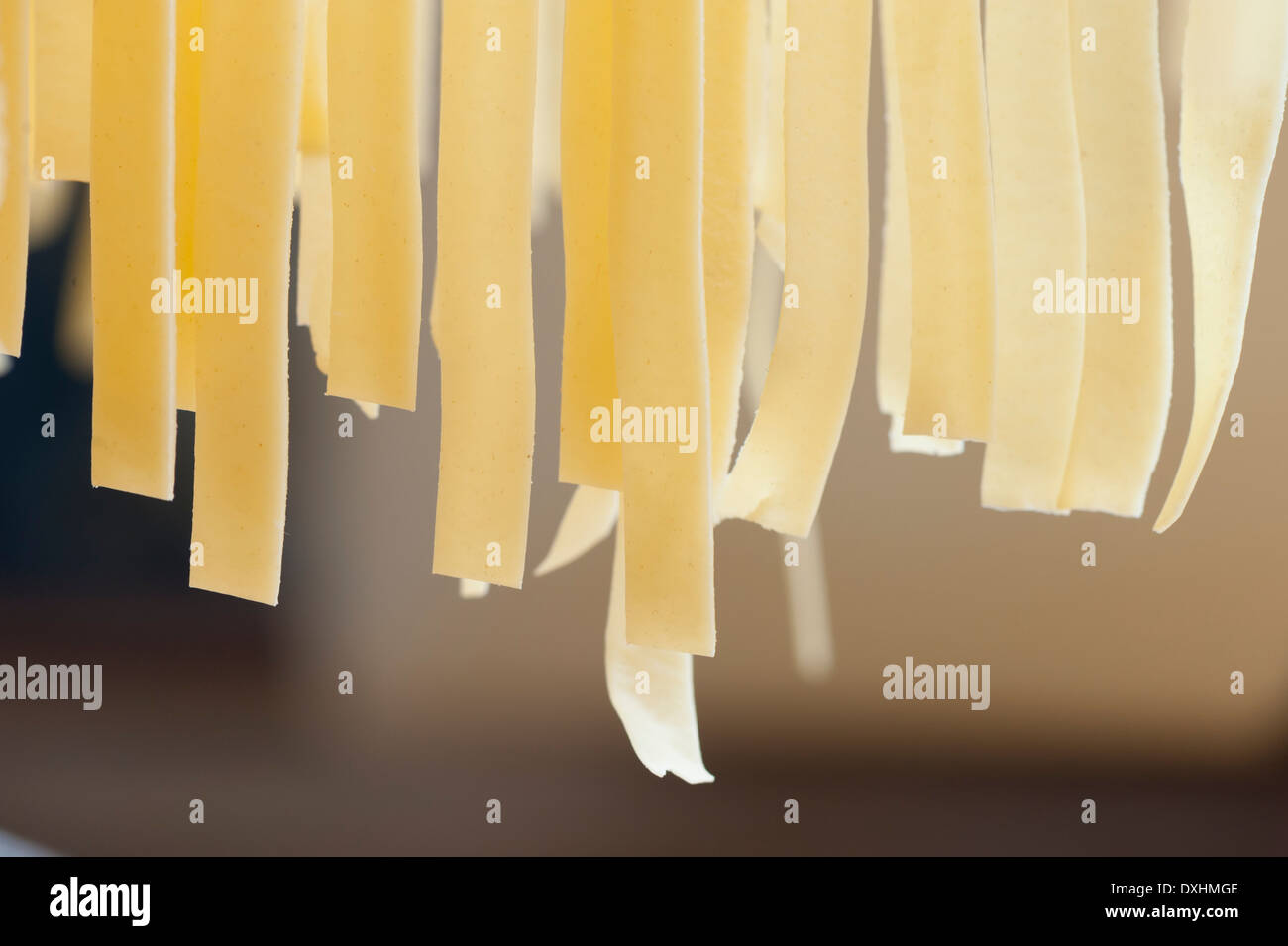 Fresh handmade Italian pasta hanging off a rack before cooking Stock ...