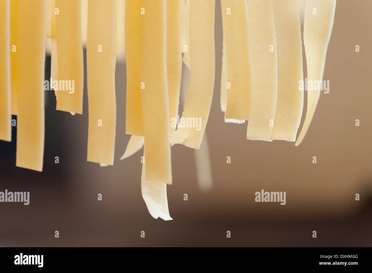 Fresh handmade Italian pasta hanging off a rack before cooking Stock ...