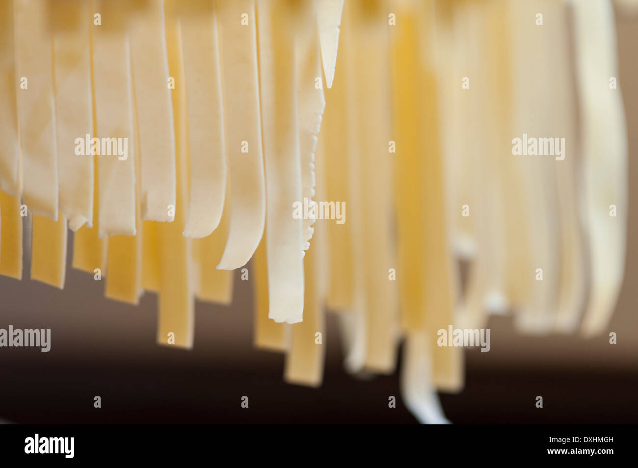 Fresh handmade Italian pasta hanging off a rack before cooking Stock ...