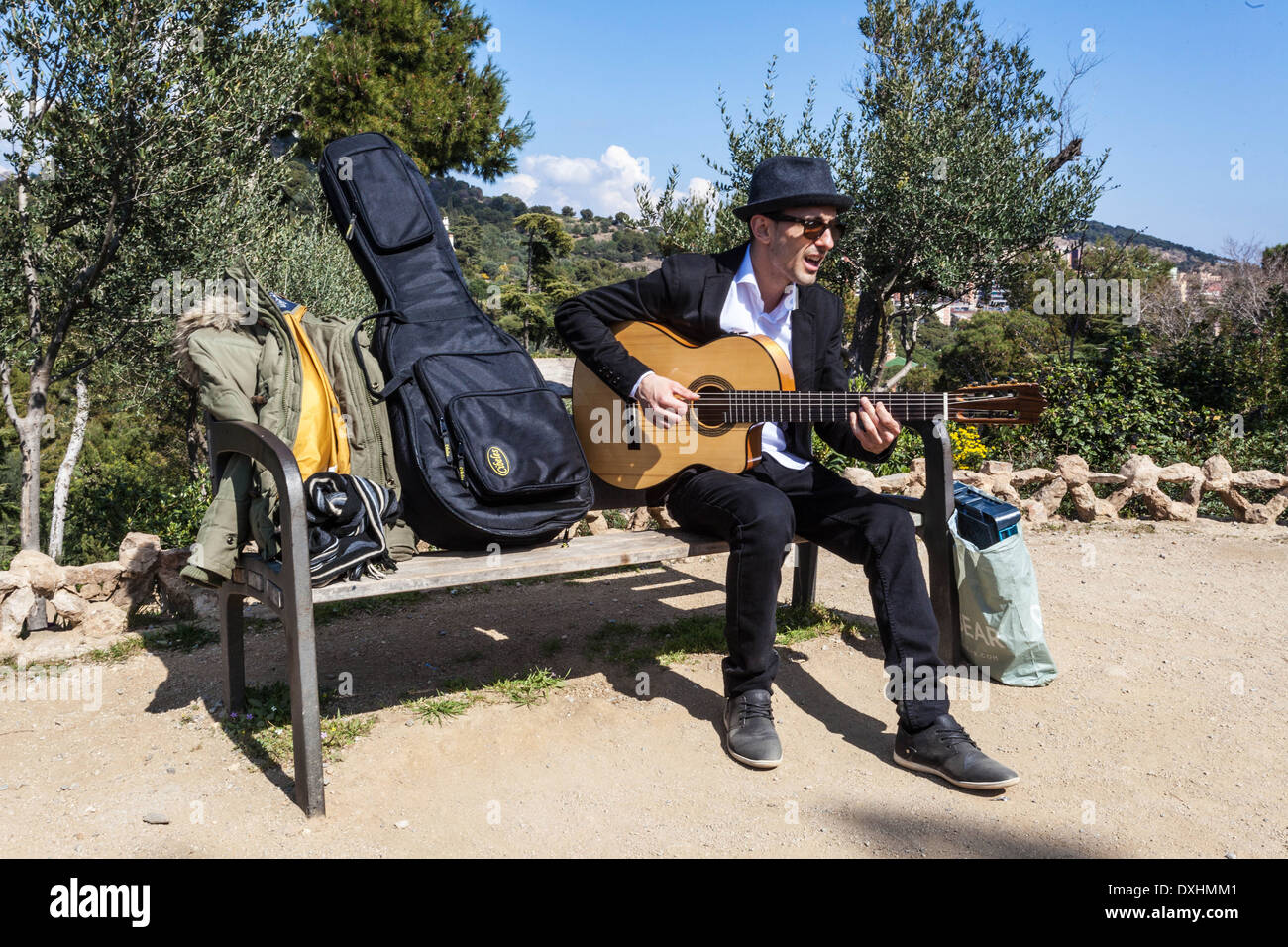 Busker playing an Spanish guitar, sitting on a bench, Park Güell ...