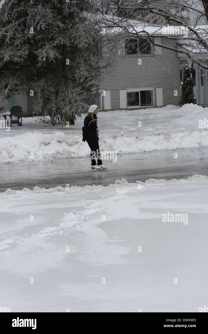 Young girl skating on an ice covered street in a residential area after ...