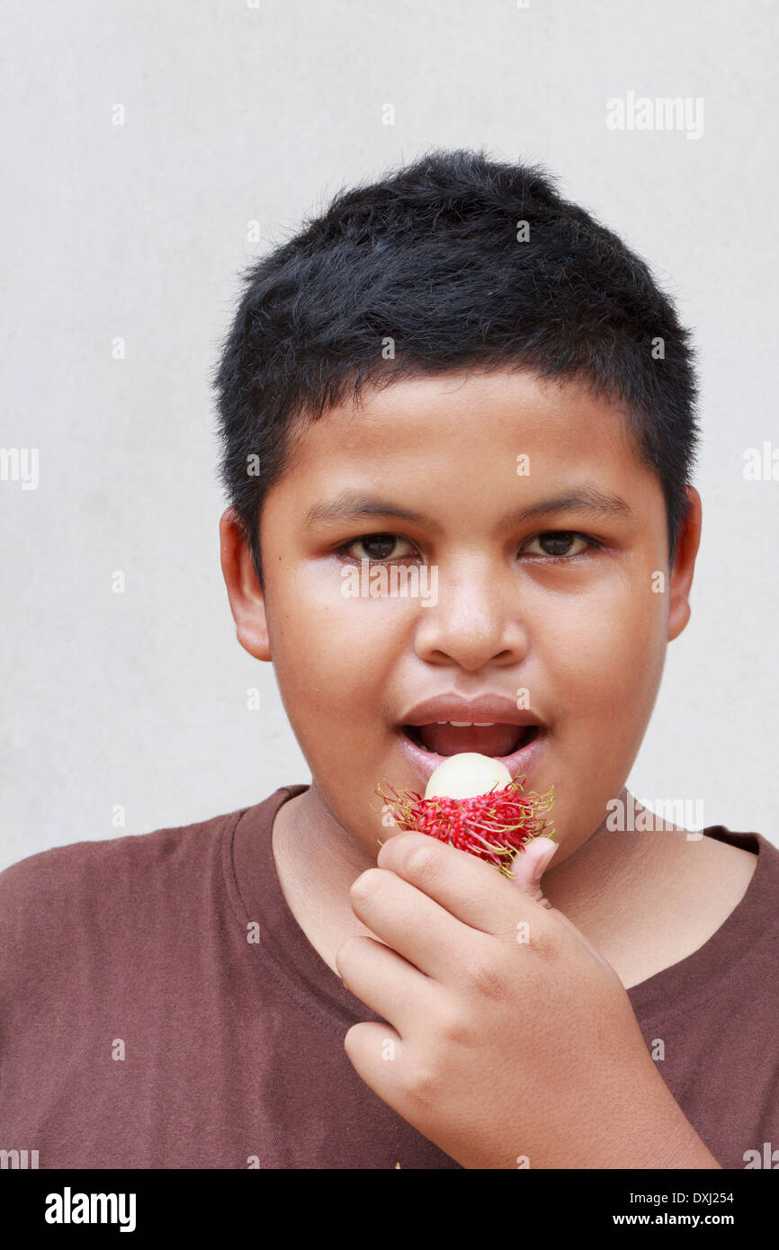 Thai teenage boy eating rambutan Stock Photo - Alamy