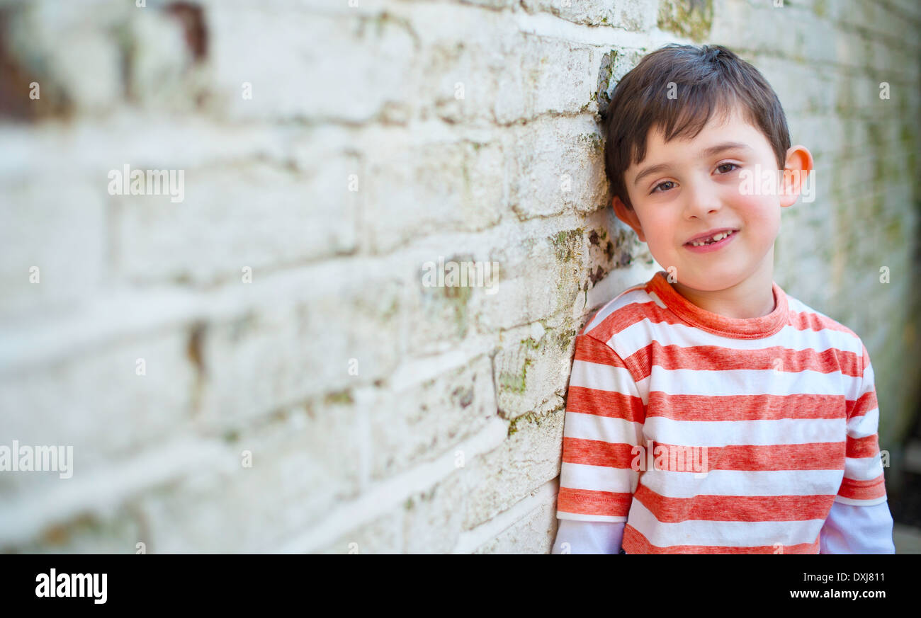 Cute boy leaning against a grungy brick wall Stock Photo - Alamy
