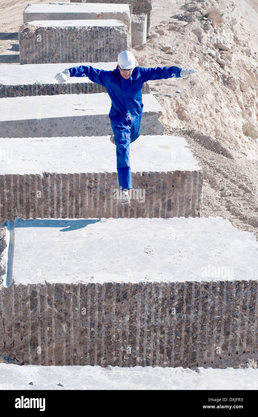 worker jumping between blocks of marble Stock Photo - Alamy