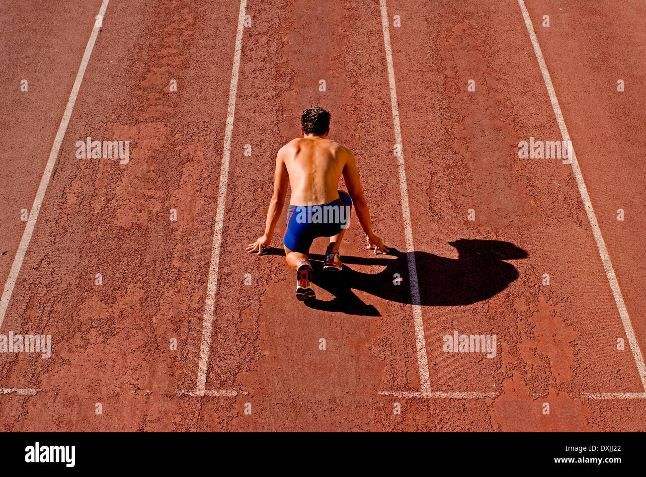 Runner on starting position of running track rear view Stock Photo - Alamy