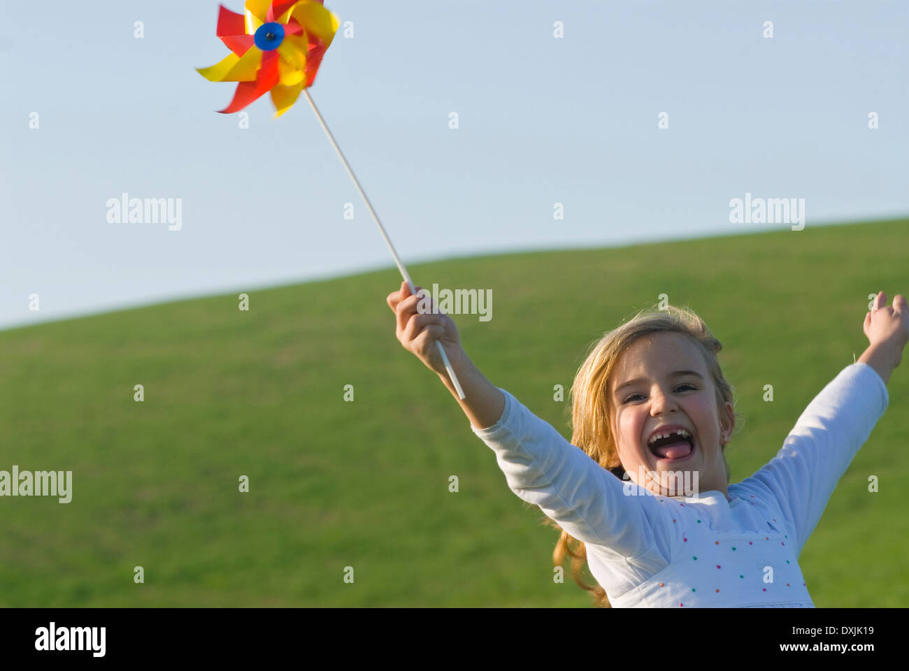 young girl with wind wheel running in green fields Stock Photo - Alamy